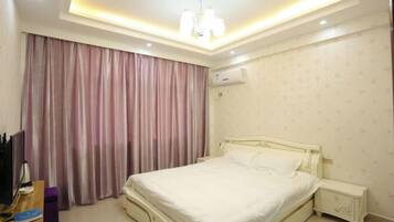 Quarto com cama, cortinas, ar condicionado, mesa de cabeceira e televisão.
