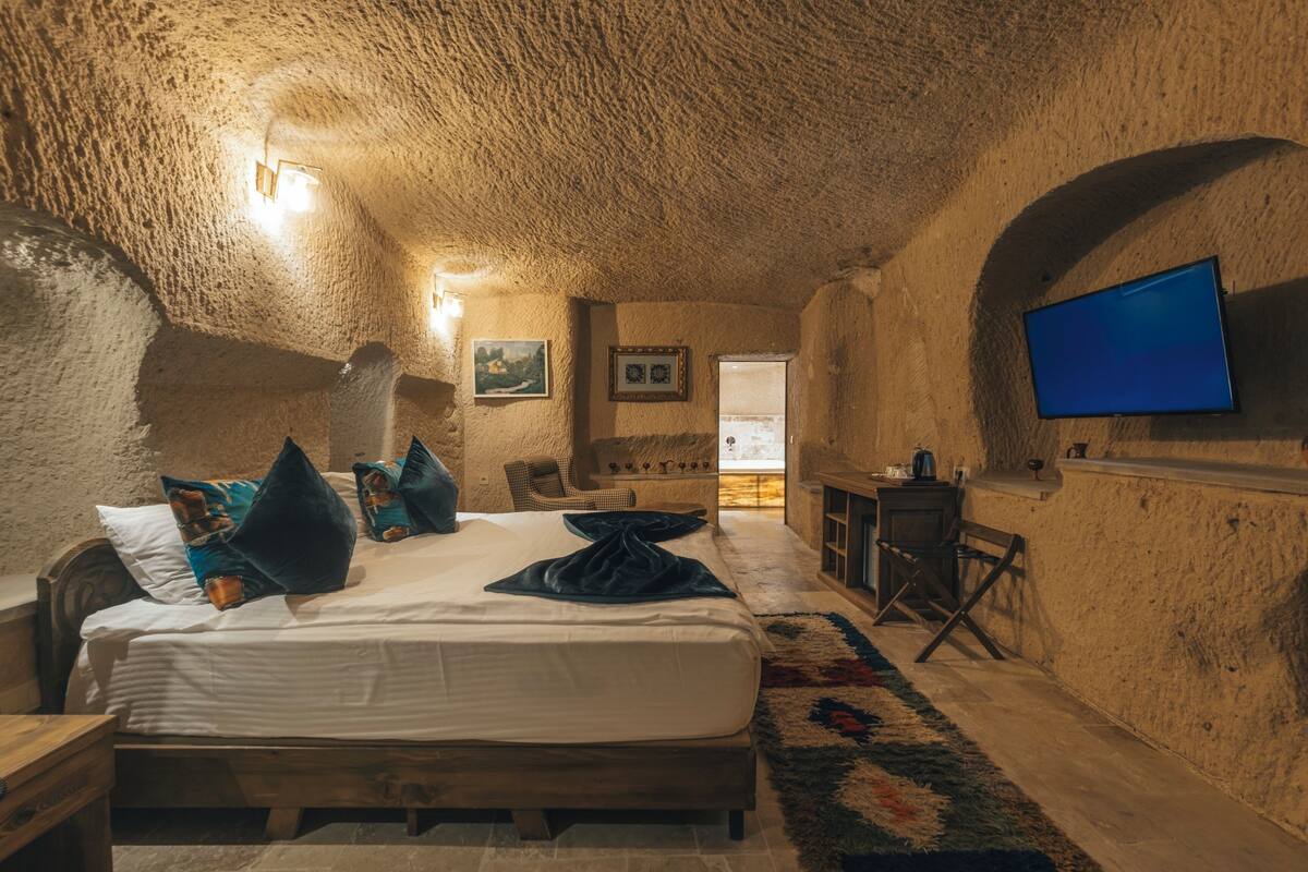 Quarto rústico e acolhedor com uma cama grande, televisão de tela plana e mesa de cabeceira de madeira.