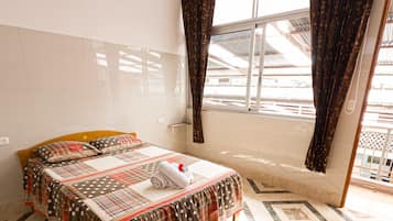 Quarto com cama, janela e vista para edifícios.