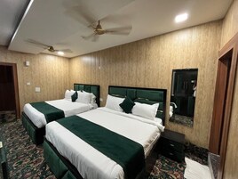 Quarto de hotel com duas camas, um ventilador de teto, um espelho e uma mesa de cabeceira.