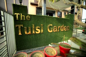 Placa para 'The Tulsi Garden', com fundo verde e letras douradas.