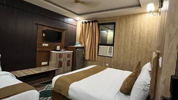 Quarto de hotel com duas camas, uma escrivaninha, uma televisão e uma janela com cortinas.