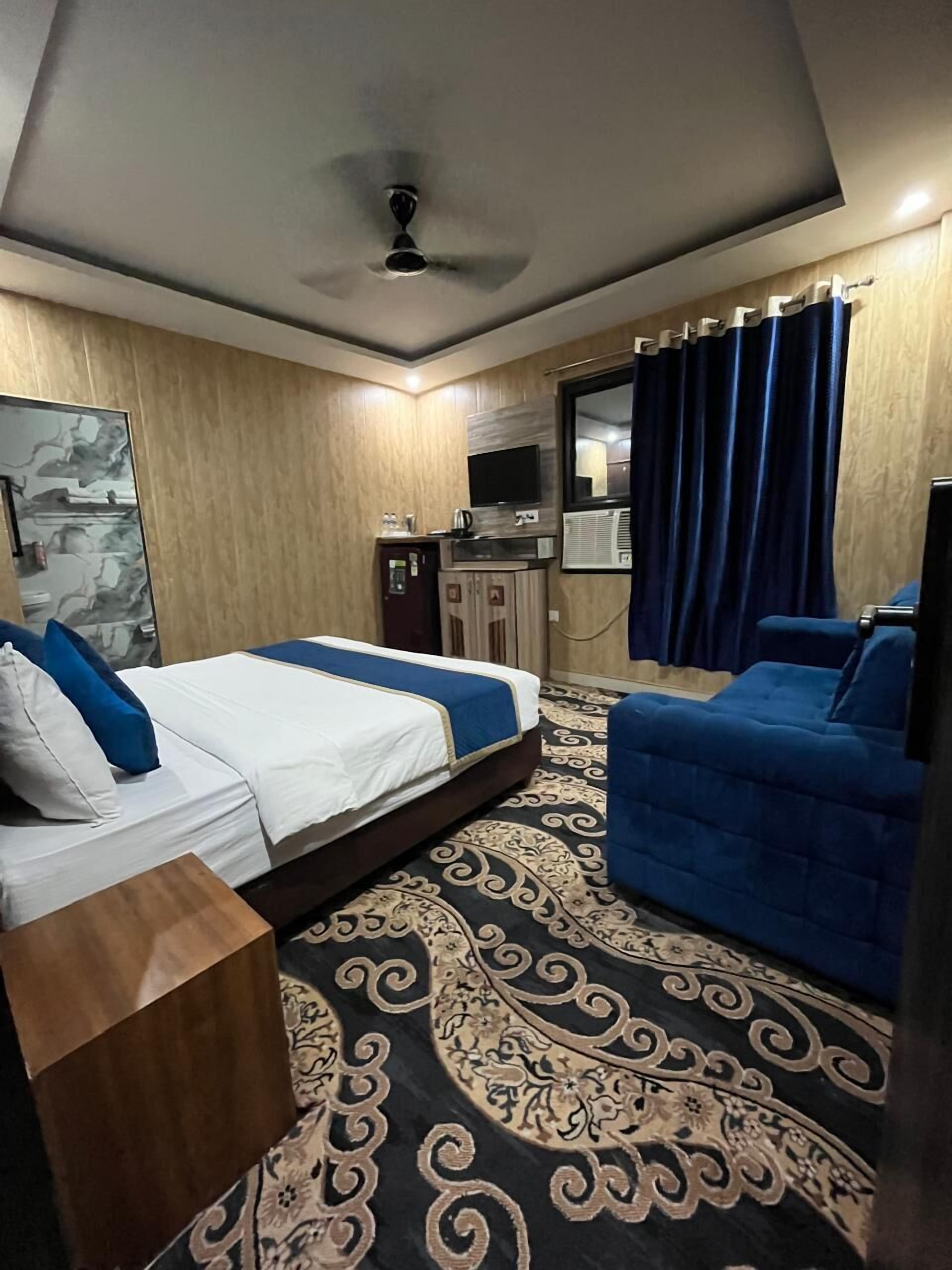 Quarto de hotel com cama, sofá, escrivaninha, televisão e minibar.