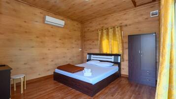 Quarto com painéis de madeira, uma cama, uma mesinha e um guarda-roupa.