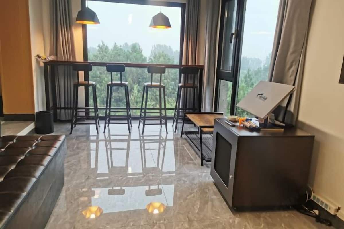 Uma sala de estar moderna com sofá, televisão, mesinha e varanda com cadeiras.