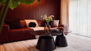 Uma sala de estar moderna com um sofá de couro, uma mesa de centro de vidro e um vaso com flores.