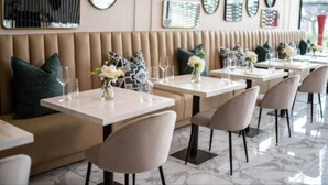 Um restaurante com cabines e mesas, cada um com um vaso de flores e taças de vinho.