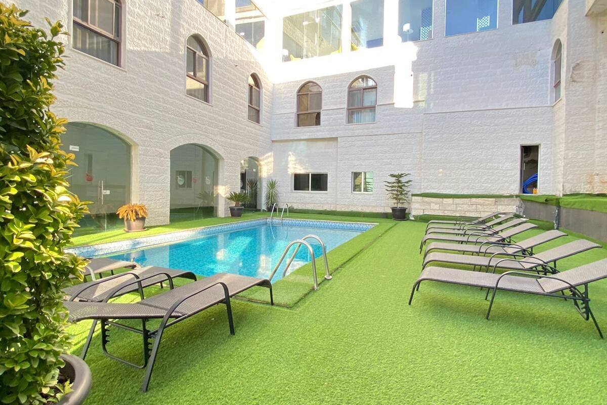 Um edifício moderno com piscina e espreguiçadeiras.