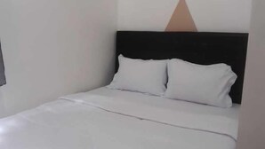 Quarto de hotel com uma cama, almofadas e uma toalha enrolada na cama.