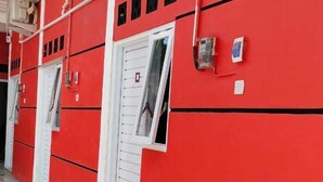 Uma fileira de armários vermelhos com portas brancas, dutos de ventilação e piso de azulejos.