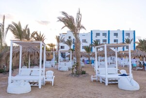 Um hotel à beira-mar com cabanas brancas, palmeiras e um edifício com detalhes em azul.