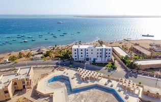 Vista aérea de um hotel à beira-mar, com piscina, acesso à praia e vista para o mar.