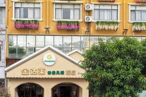 Um edifício com fachada amarela, várias janelas e uma placa com logotipo e caracteres chineses.