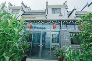 Um edifício tradicional com entrada de vidro, rodeado por vegetação.