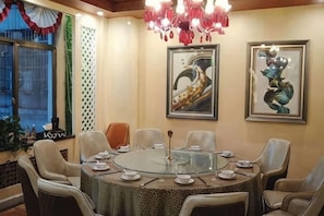 Uma área de refeições com uma mesa redonda, cadeiras e obras de arte nas paredes.