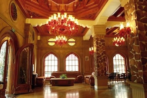 Um hall imponente com um grande lustre, janelas em arco e uma parede de pedra.