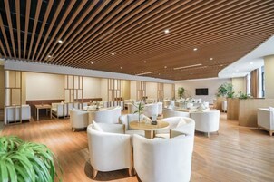 Um hall de hotel espaçoso com várias áreas de estar, teto de madeira e balcão de recepção.