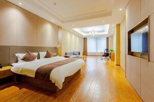 Quarto de hotel moderno com uma cama grande, uma escrivaninha e uma televisão.