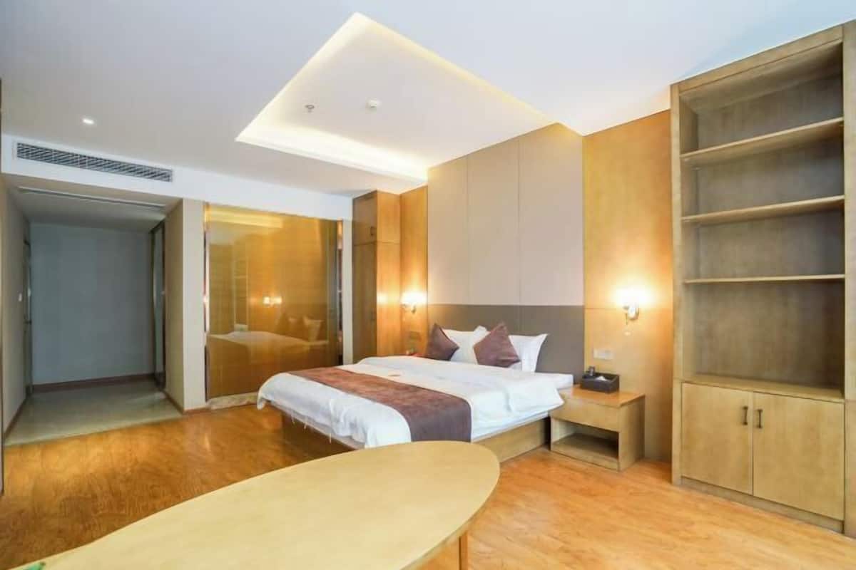 Quarto de hotel moderno com uma cama grande, mesas de cabeceira, guarda-roupa e escrivaninha.