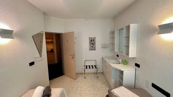 Casa de banho pequena e compacta com lavatório branco, espelho e porta-toalhas.