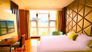 Quarto de hotel com uma cama, uma escrivaninha, uma cadeira e uma televisão.