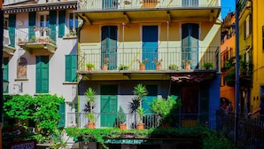 Um edifício de vários andares com varandas, vasos de plantas e uma placa para um bar de vinhos.