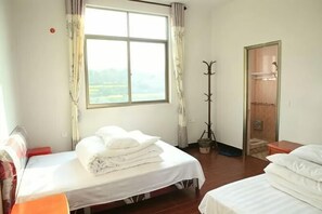 Quarto com duas camas, uma janela com cortinas, um cabideiro e uma porta.