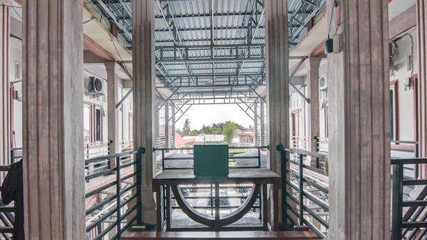 Uma galeria coberta com um banco no centro, ladeada por grades e colunas.