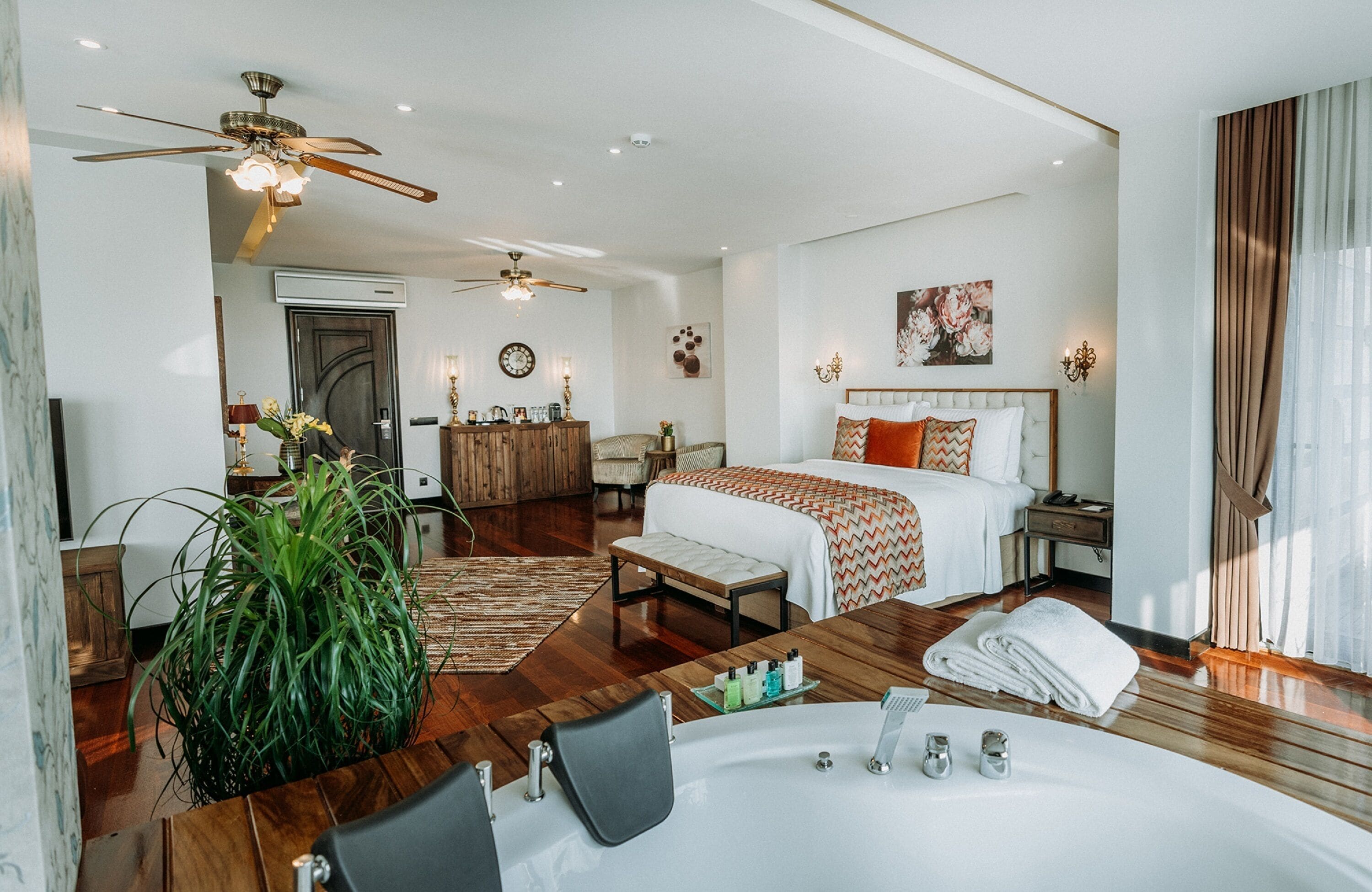 Quarto de hotel moderno com uma cama grande, área de estar, escrivaninha e banheiro com banheira.