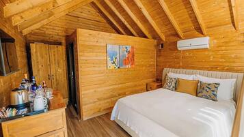 Quarto de cabana de madeira com cama, mesa de cabeceira, cômoda e um quadro na parede.