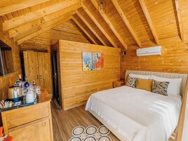 Quarto de cabana de madeira com cama, mesa de cabeceira, cômoda e um quadro na parede.
