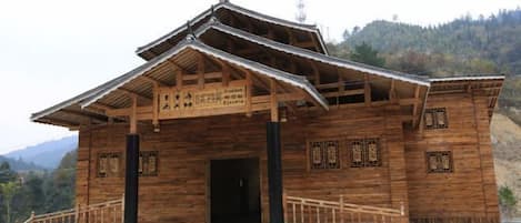 Um edifício de madeira tradicional com telhado inclinado e escadaria que leva à entrada.