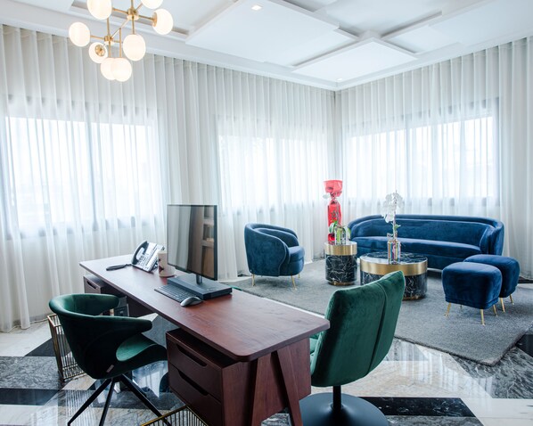Um espaço de escritório moderno com uma mesa, computador e cadeiras verdes.