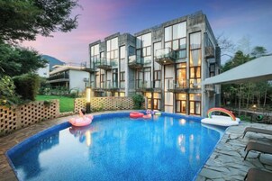 Um edifício moderno com piscina, área de estar externa e jardim paisagístico.