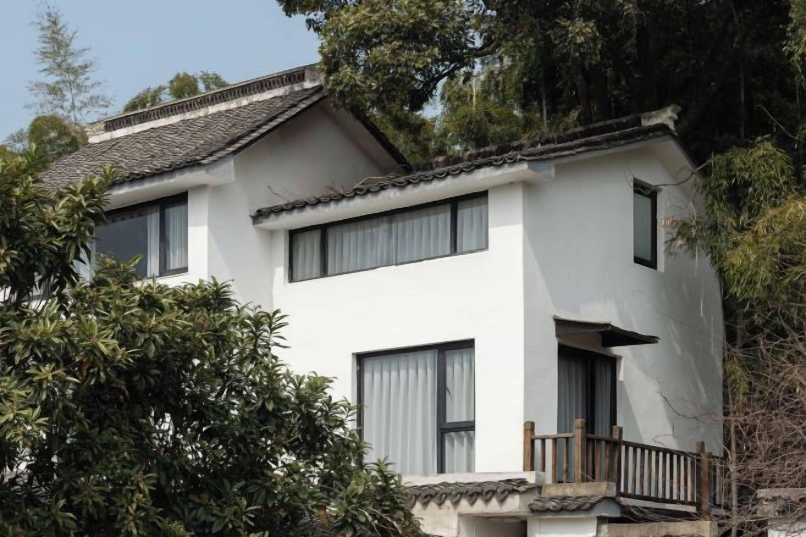 Um edifício de dois andares com fachada branca, grandes janelas e varanda.