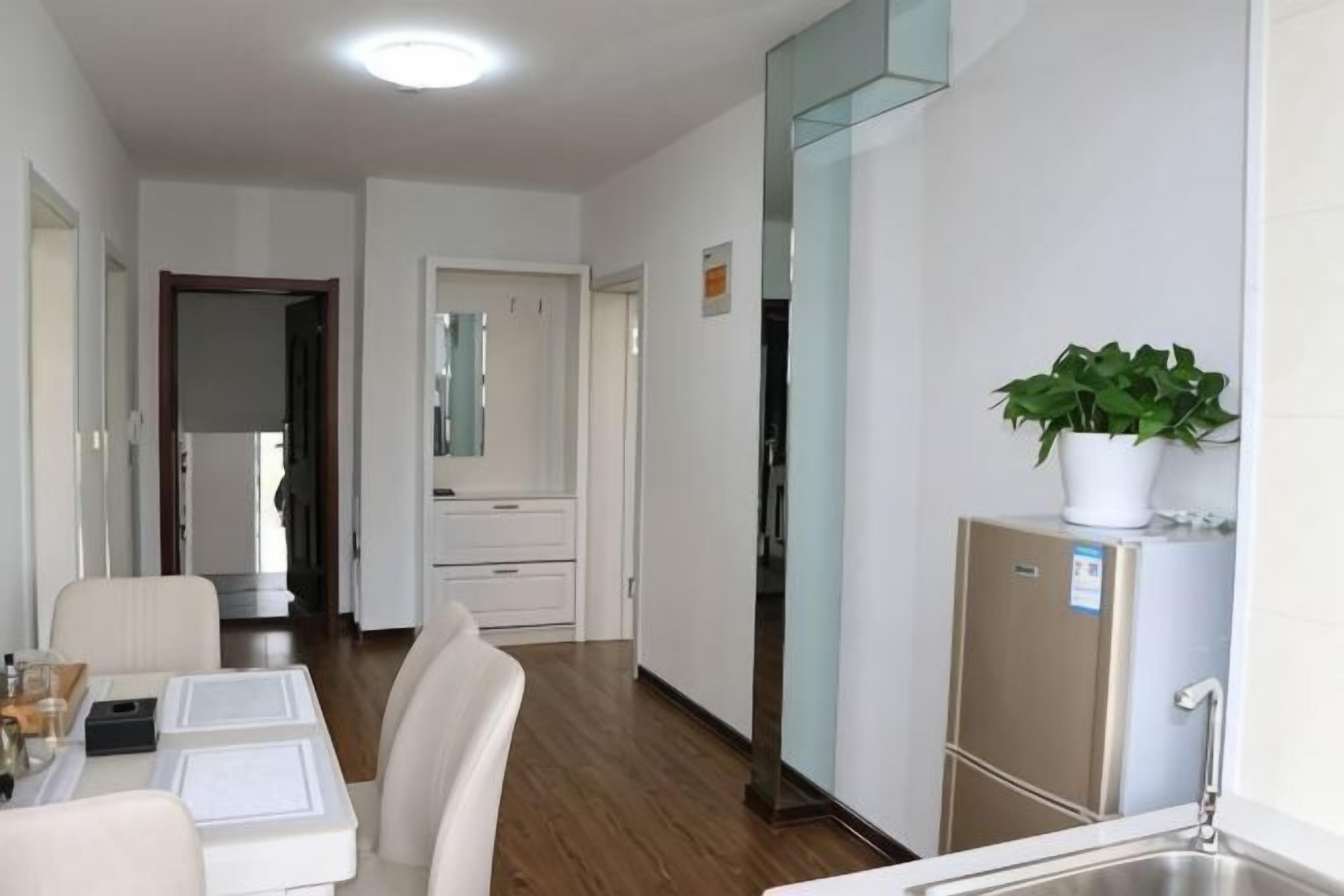 Quarto de hotel com cozinha compacta, área de refeições, espelho e planta em vaso.