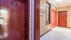 Corredor de hotel com portas de madeira, balcão de recepção e piso de azulejos.