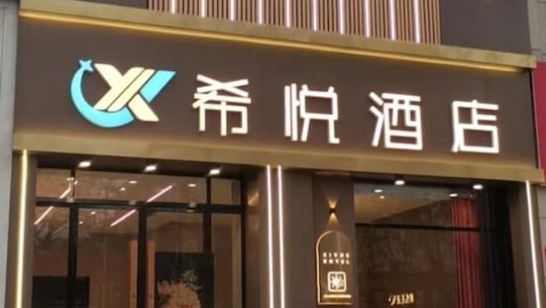 Entrada de um hotel com uma placa que diz 'Xingfu Hotel'.