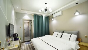 Quarto de hotel com cama, mesa de cabeceira, escrivaninha com cadeira, televisão e janela com cortinas.