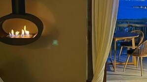 Quarto com lareira, varanda com mesa e cadeiras, e vista do céu noturno.