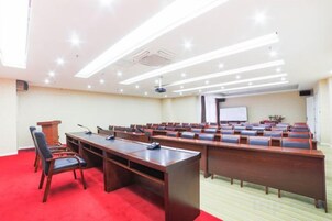Uma sala de conferências com uma mesa comprida, cadeiras, um pódio e uma tela de projetor.