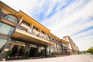 Um hotel com fachada moderna, grandes janelas e área de entrada coberta.