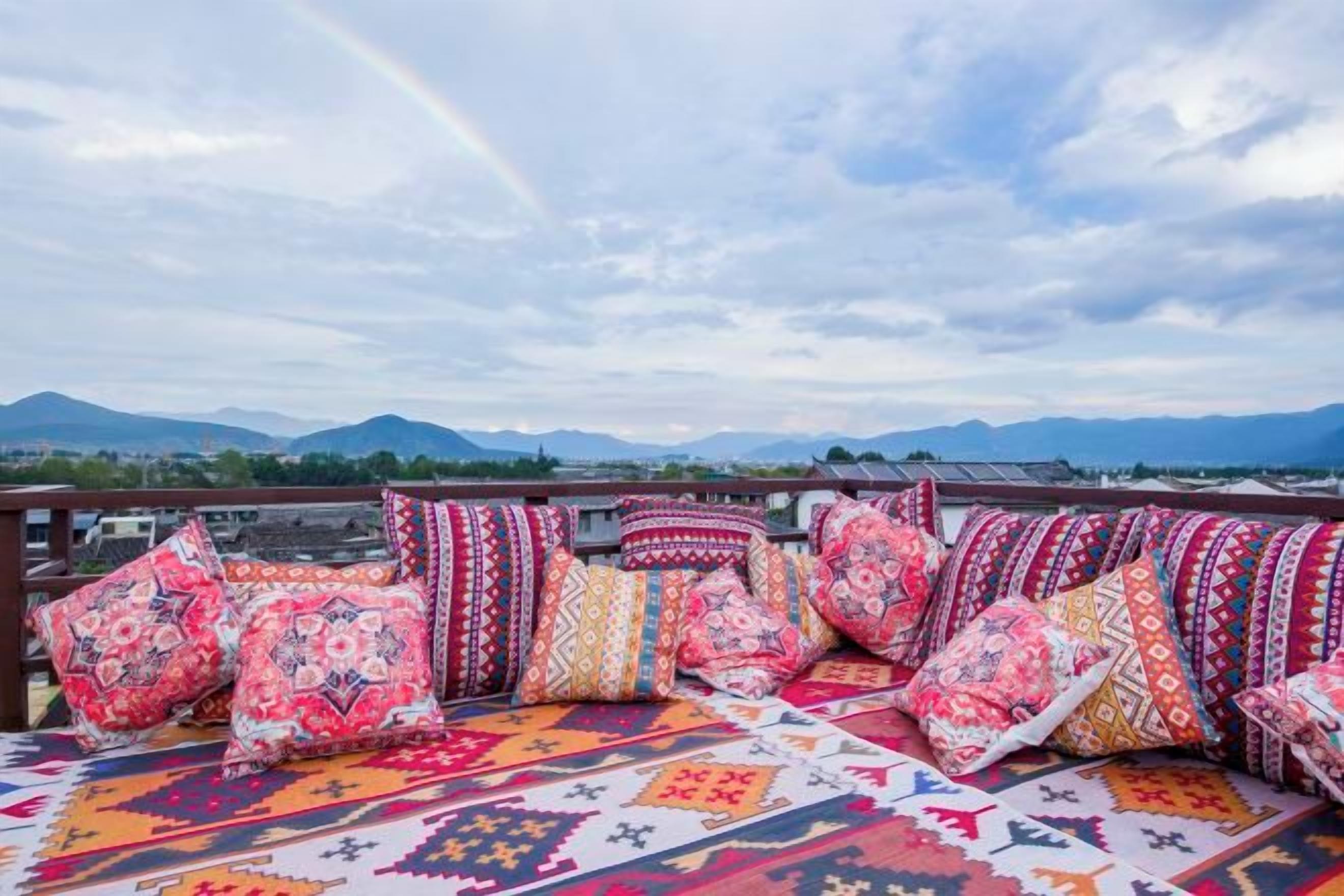 Área de estar no terraço com almofadas estampadas e vista para montanhas.