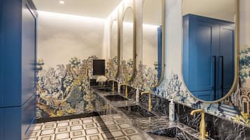Um banheiro com piso ladrilhado, pia de mármore e armário azul.