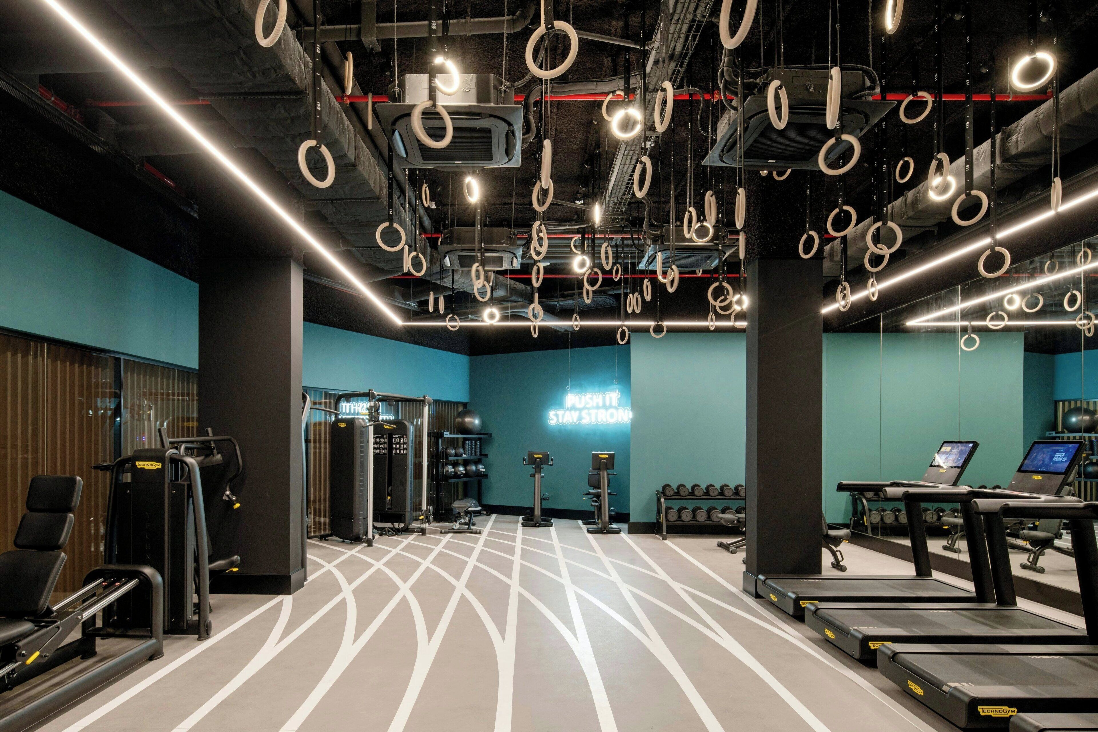 Uma academia com equipamentos de ginástica, esteiras e um painel motivacional.