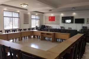 Uma sala de conferências com uma mesa comprida, cadeiras, tela de projetor e uma televis ão.