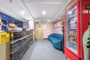 Uma área de recepção de hotel com balcão, sofá azul e máquina de venda automática.