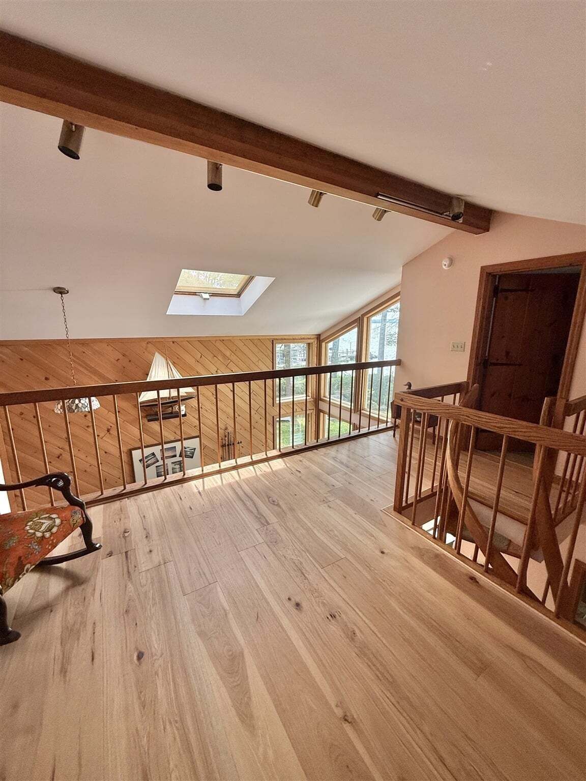 Um loft espaçoso com piso de madeira, um claraboia e vista para o exterior.