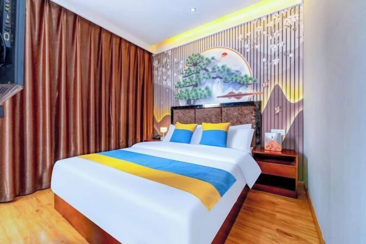 Quarto com cama grande, piso de madeira e parede com um mural decorativo.