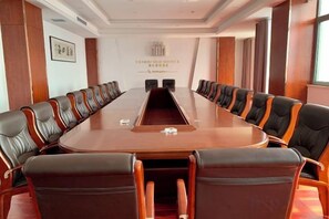 Uma sala de conferências com uma mesa comprida e várias cadeiras, um logotipo na parede e uma janela que oferece iluminação natural.